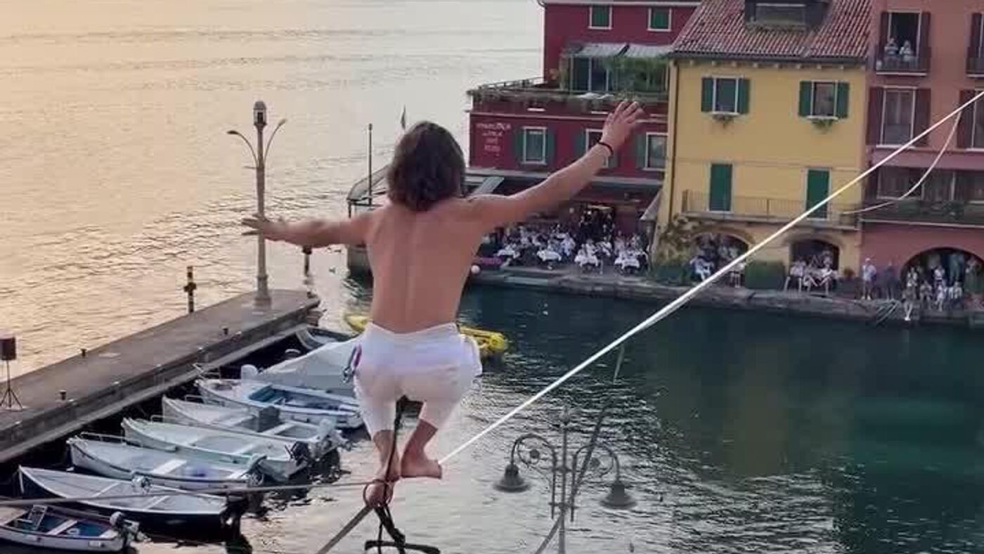 Un funambule stupéfie la foule en traversant le port sur un fil tendu ...